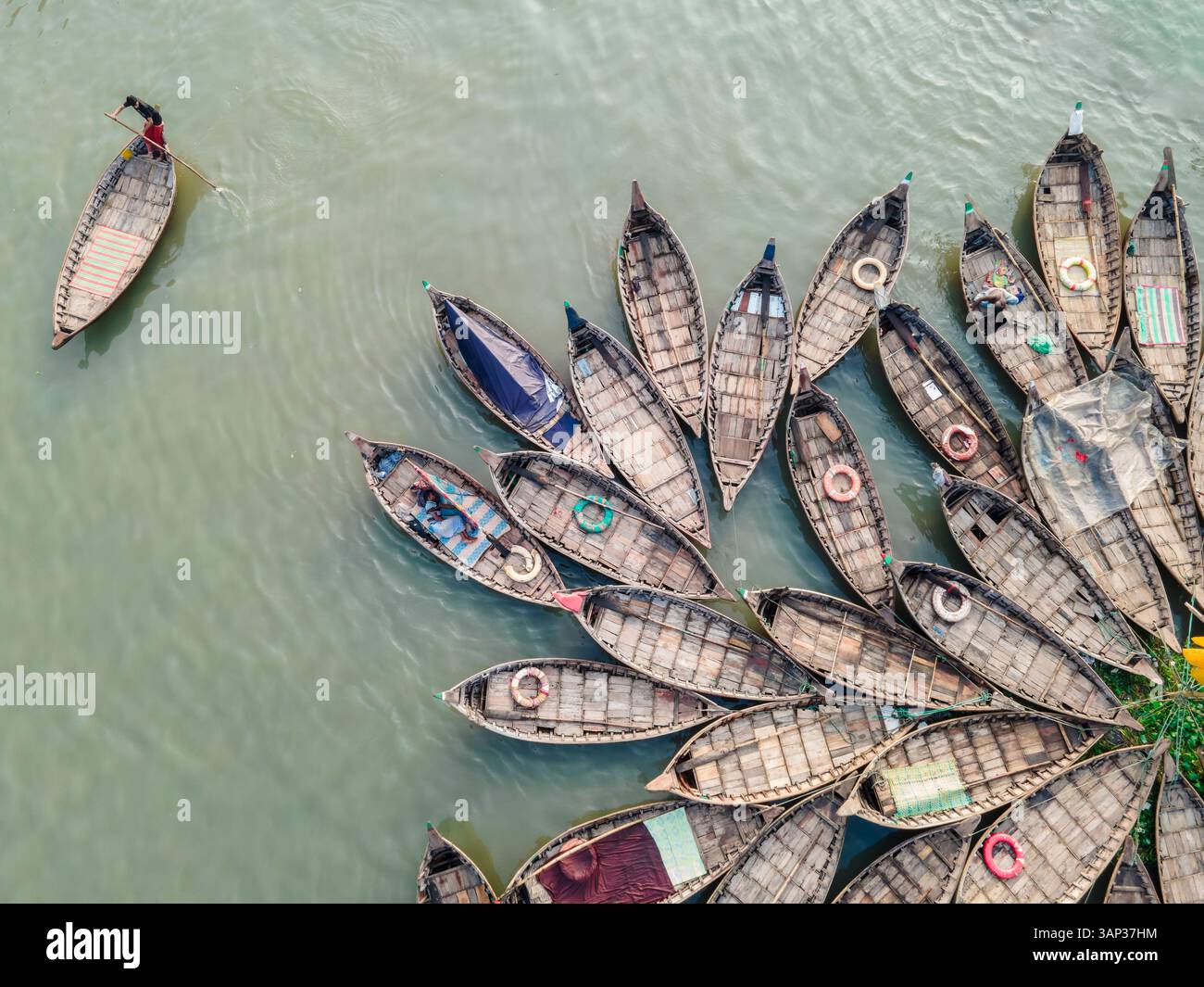 Aerial view of colorful boats on the Buriganga River with workers commuting in a bustling urban ...