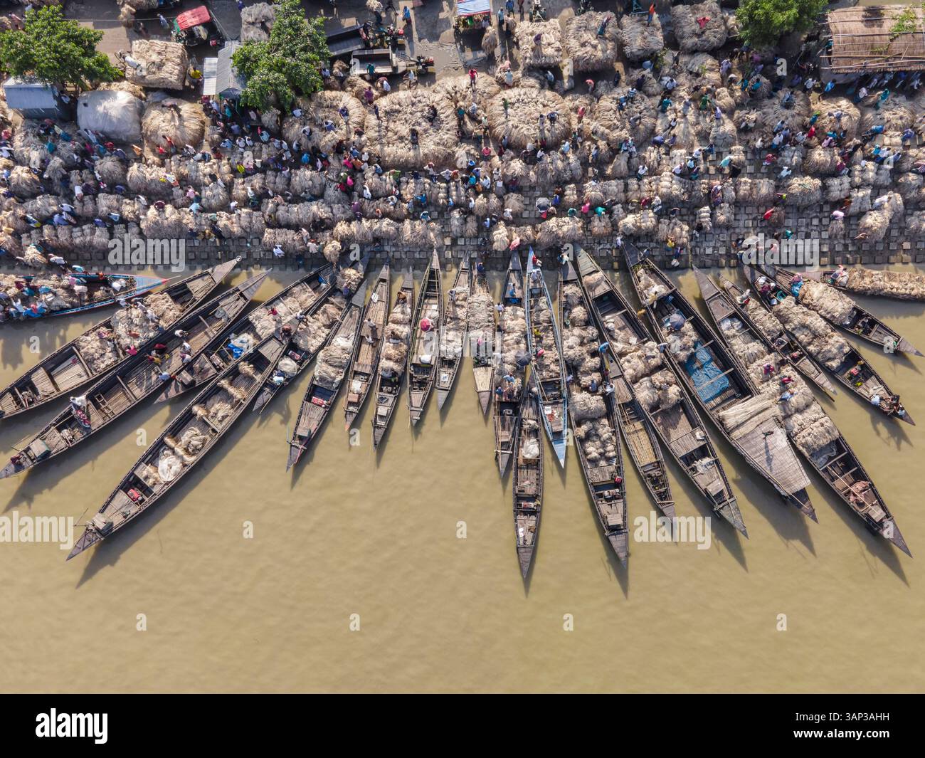 Aerial view of a busy jute market with traditional boats on the river ...