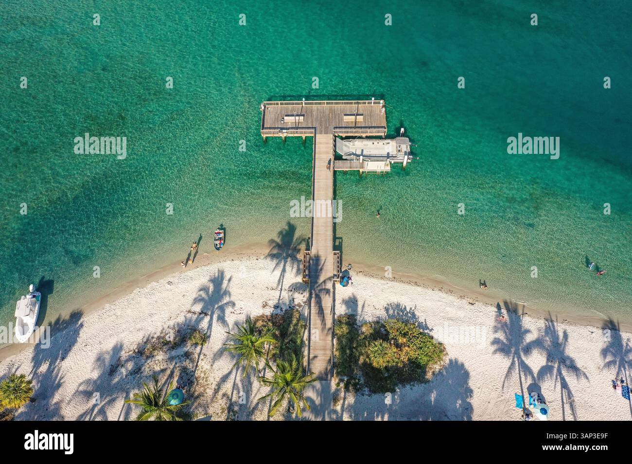 Aerial view of a boat dock with blue clear waters on a white sandy ...