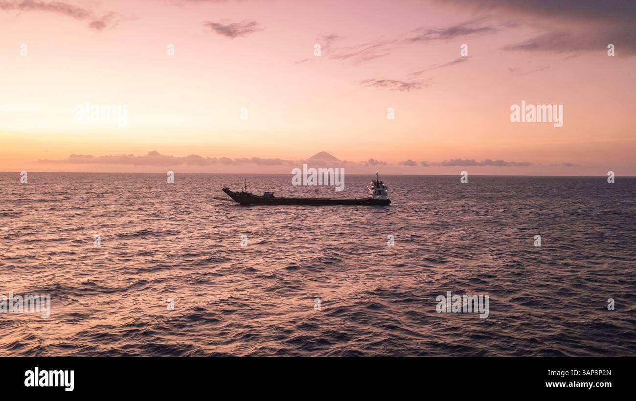 Aerial view of a large freight ship in front of Bali's Mount Batur ...