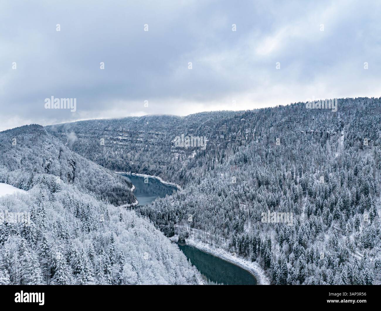Aerial view of snowy landscape in the valley of River Doubs surrounded ...