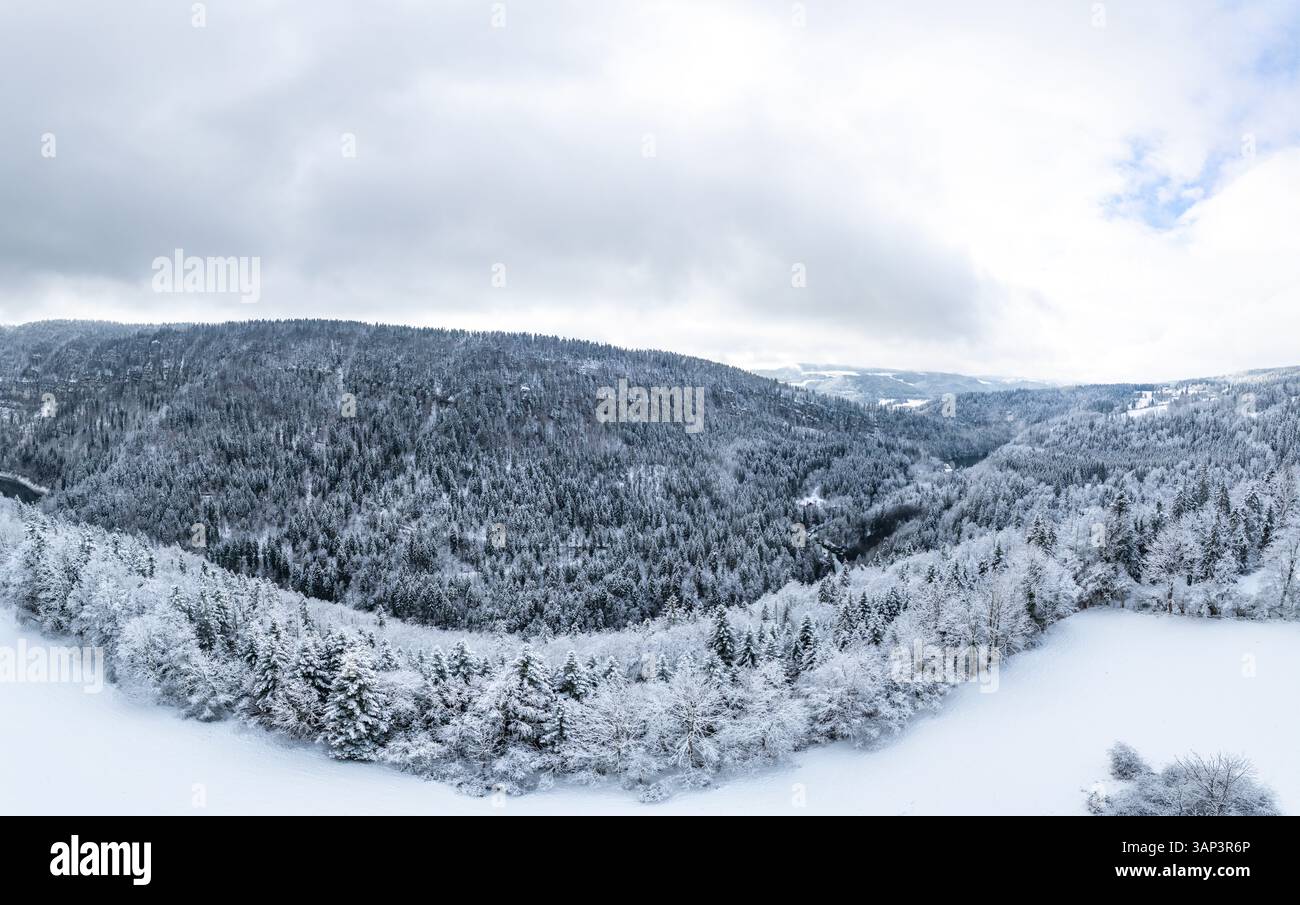 Aerial view of snowy landscape in Valley of River Doubs with forest and ...