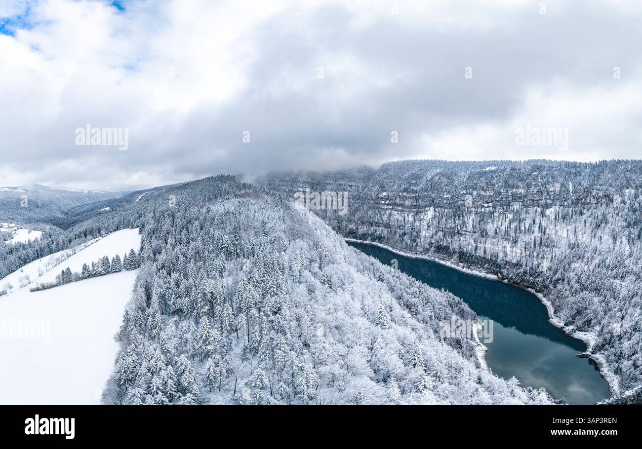 Aerial view of snowy landscape in the valley of River Doubs with forest ...