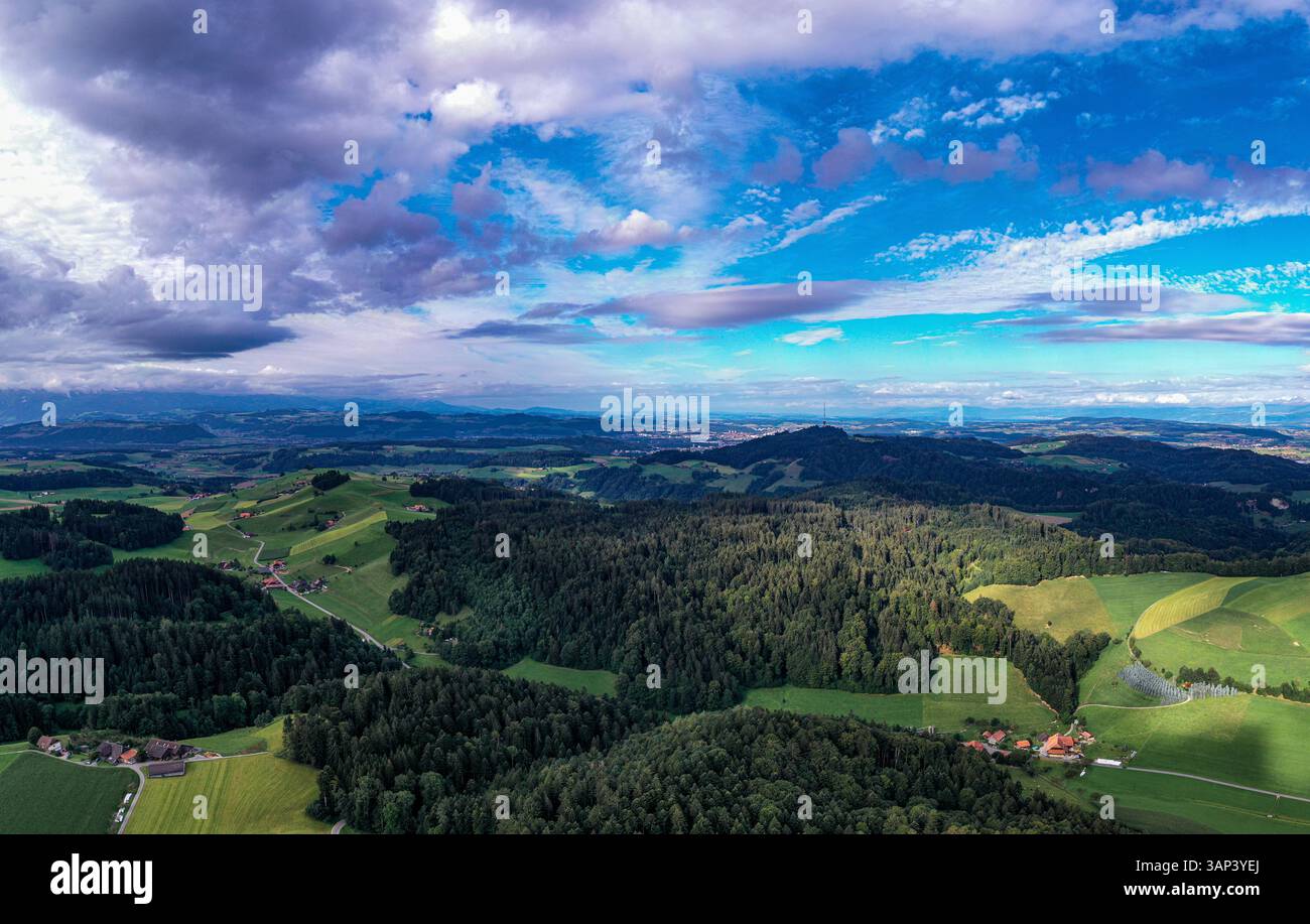 Aerial view of rolling hills, forest, and village under a serene sky ...