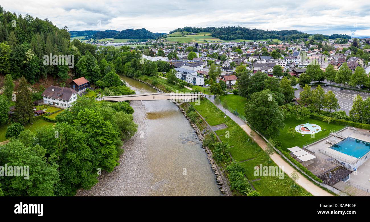 Aerial view of river Emme with bridge, houses, trees, and forest ...