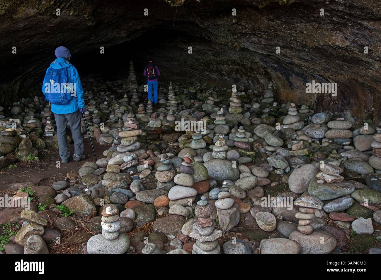 Walkers inspecting stacked stones in the King's Caves at Drumadoon near ...