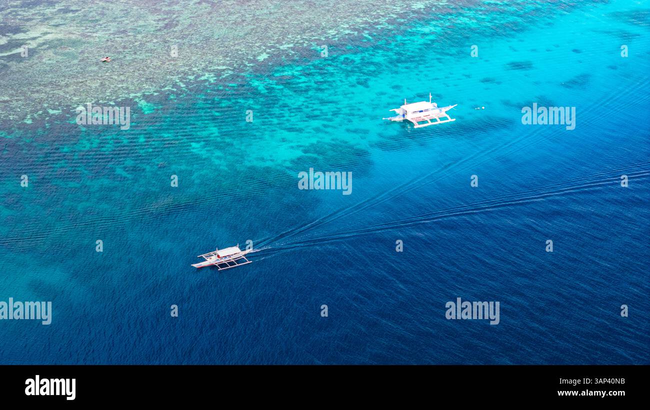 Aerial drone view of fishing boat in vibrant ocean water on the island ...