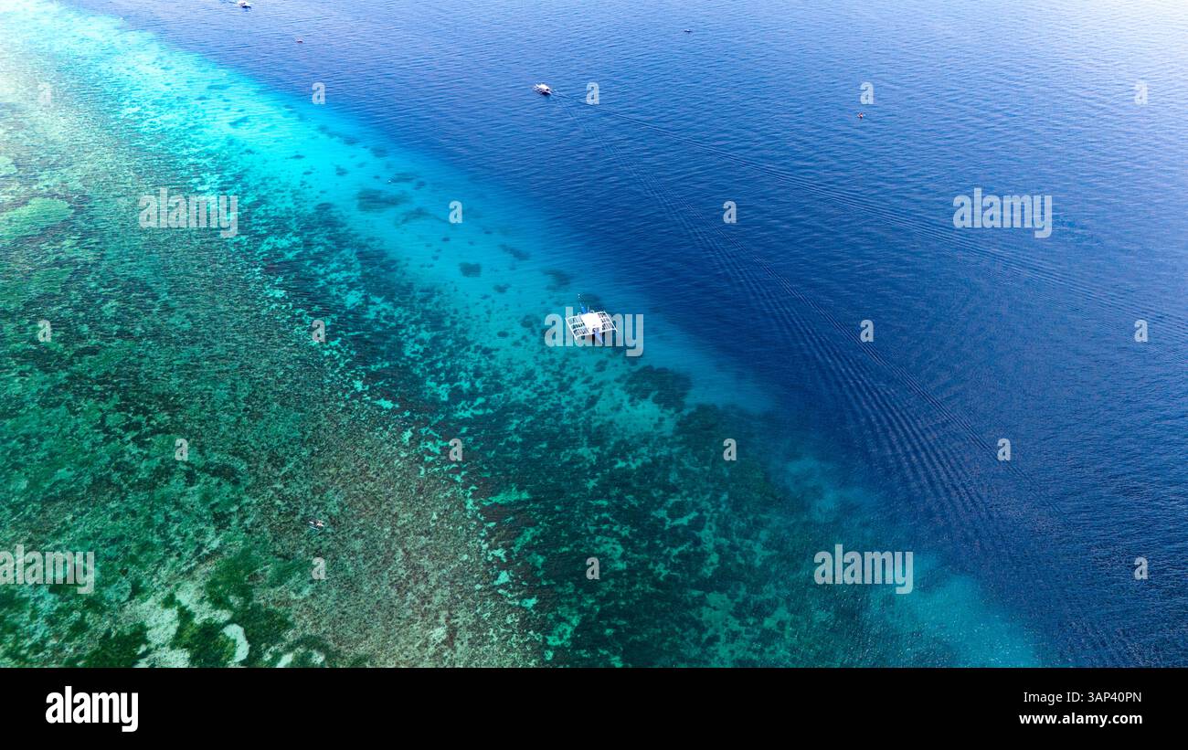 Aerial drone view of fishing boat in vibrant ocean water on the island ...