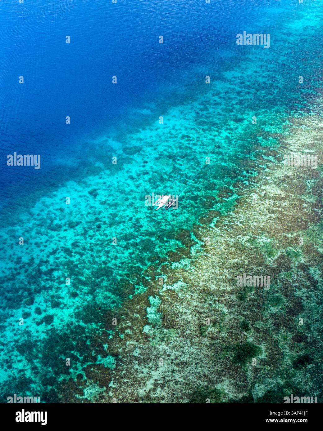 Aerial drone view of fishing boat in vibrant ocean water on the island ...