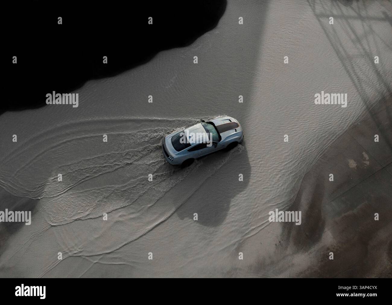 Aerial view of the Ford Mustang Mach 1 driving true a large puddle ...