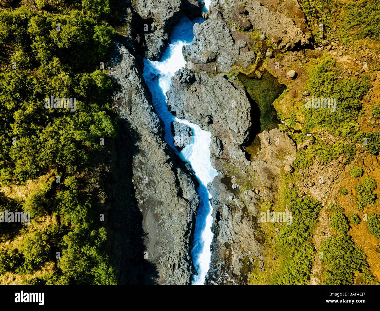 Aerial view of hraunfossar waterfall cascading through lush greenery ...