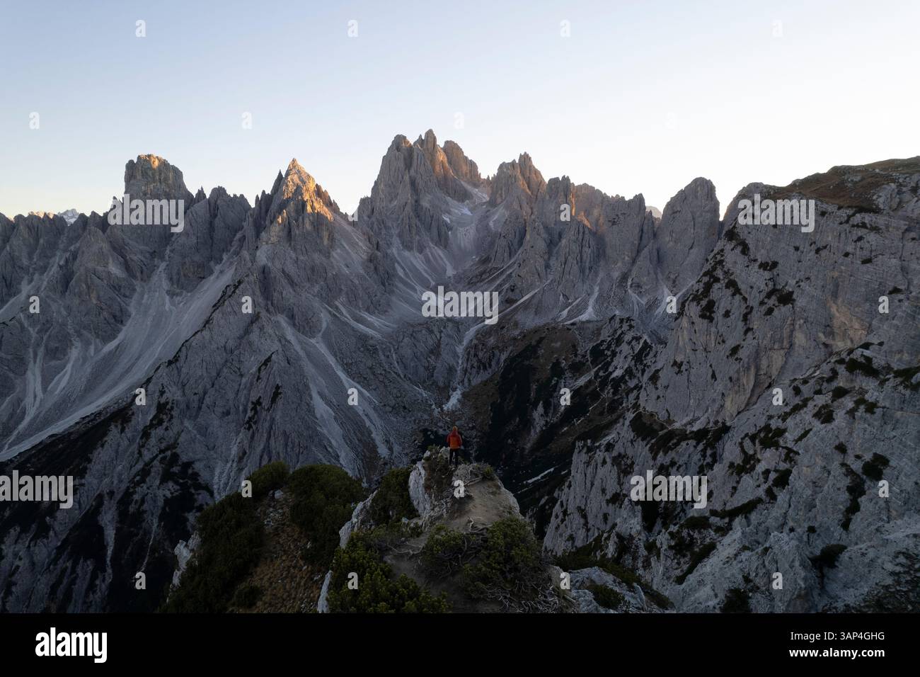 Aerial view of a hiker climbing a mountain crest with Three peaks of ...