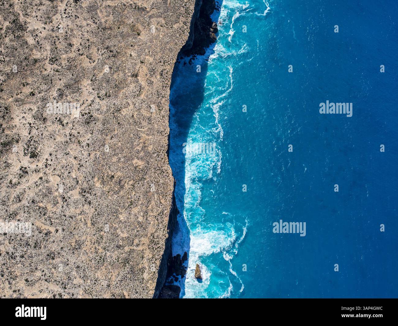 Aerial view of rugged cliffside and blue water along Baxter Cliffs ...