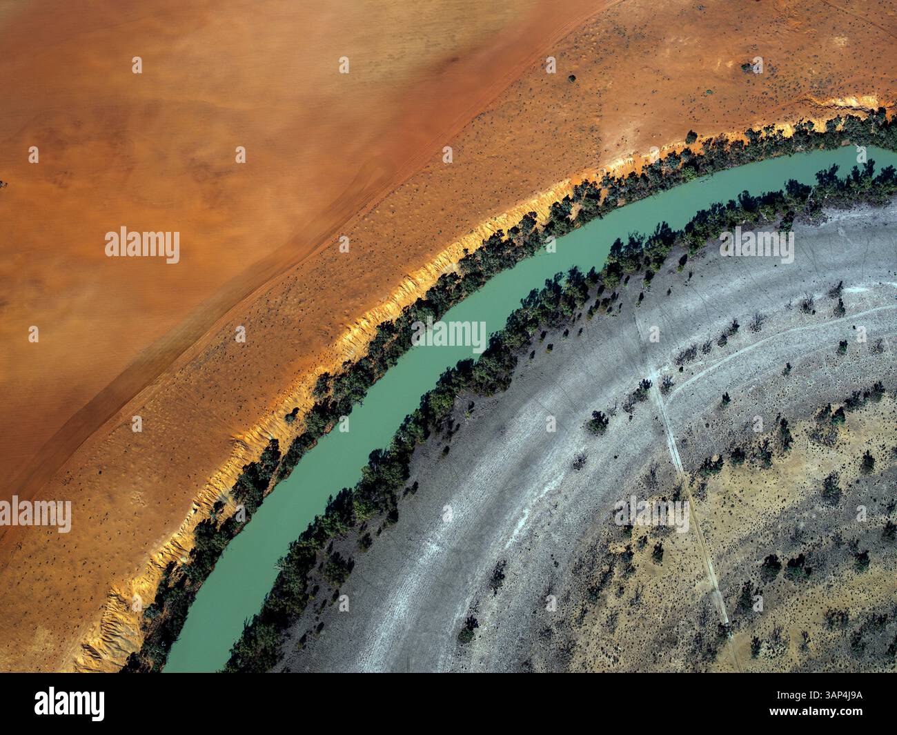 Aerial view of winding river with green water and desert landscape ...