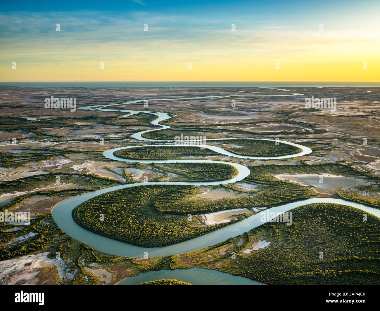 Aerial view of meandering river through pristine wetlands at sunset ...