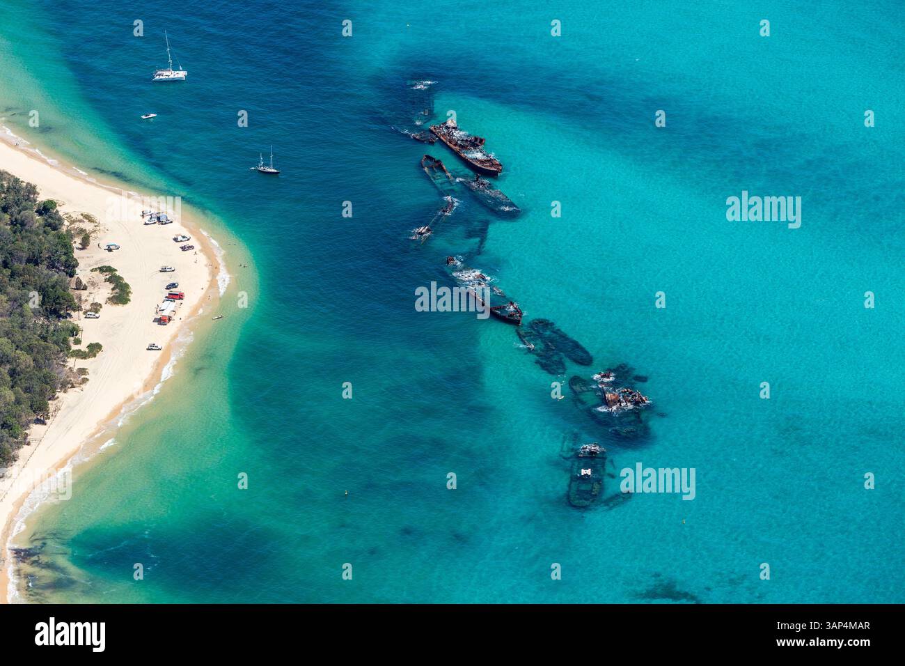 Aerial view of shipwrecks, beach, and sailboats on turquoise ocean ...