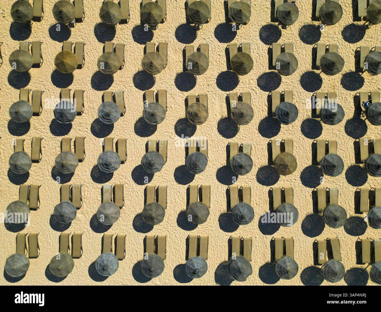 Aerial view of sunlounger and umbrella pattern on sandy beach ...
