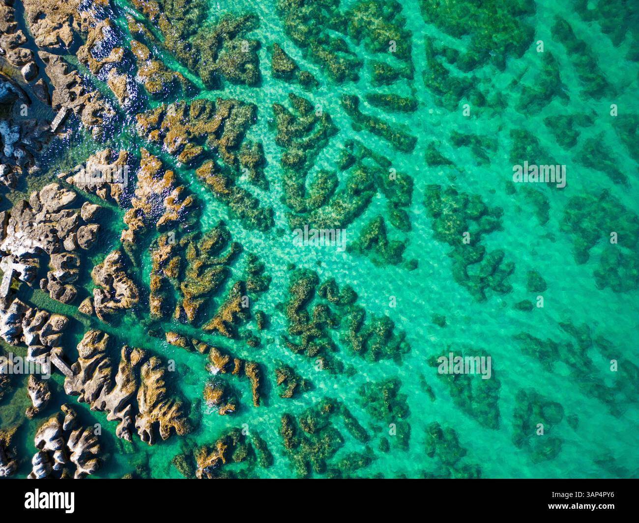 Aerial view of crystal clear water along the coastline with rocky ...