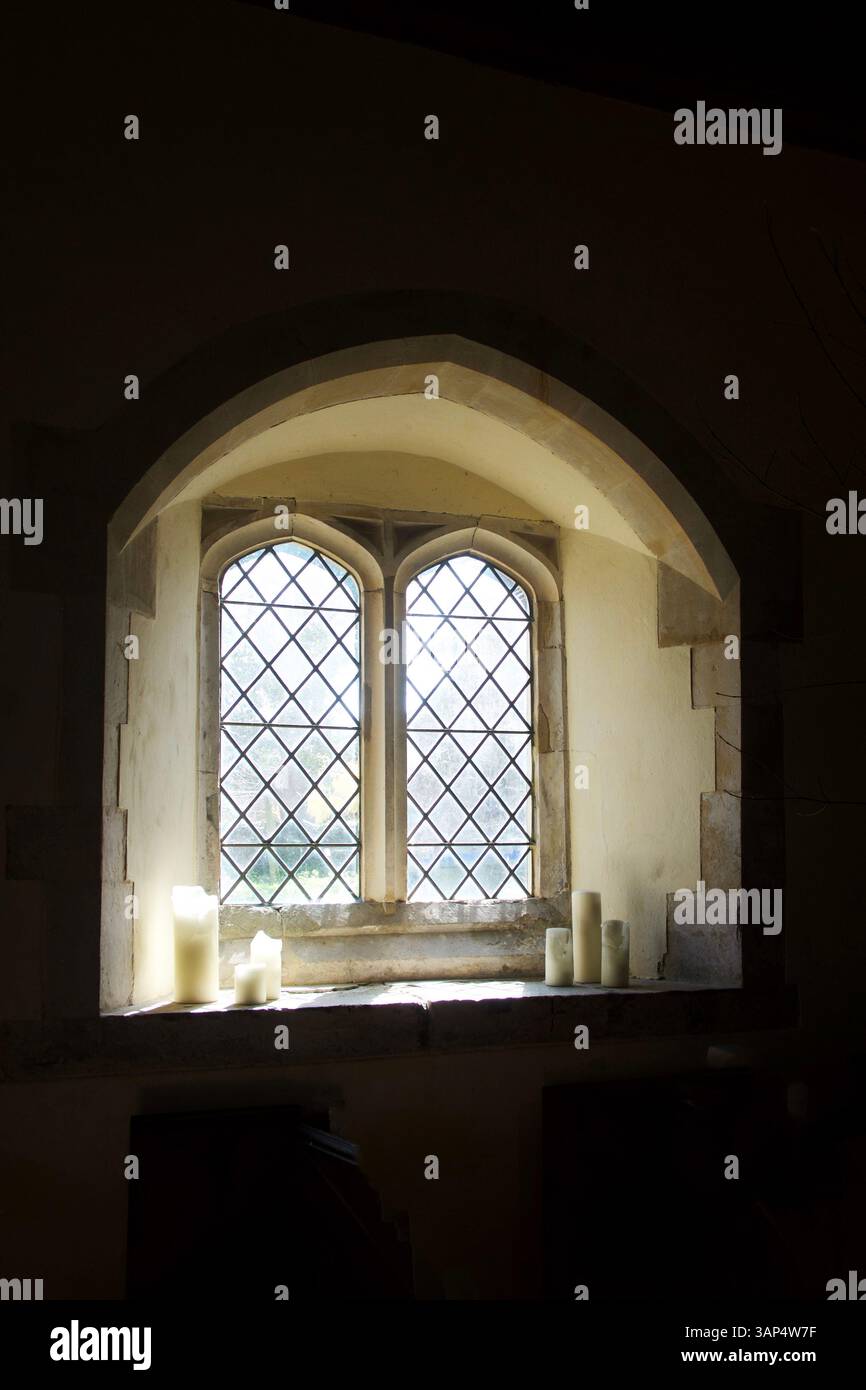 light streaming through a church window with three white candles on ...