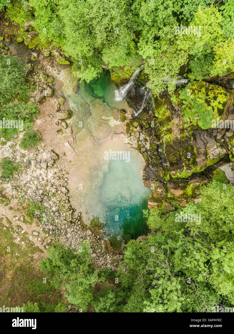 Aerial view of the top of a small waterfall with clean water downhill ...