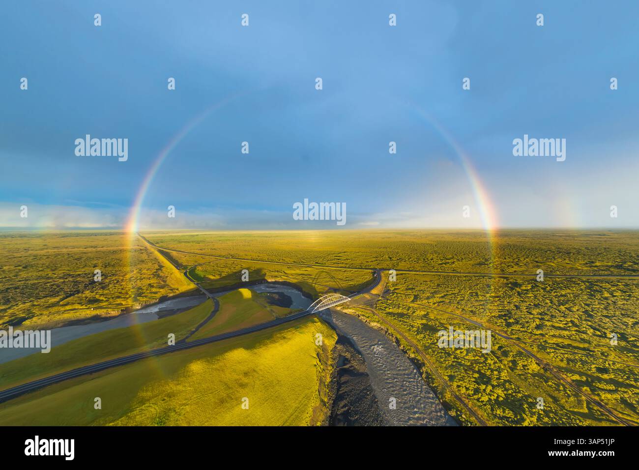 Aerial view of full rainbow over green landscape with road, river and ...