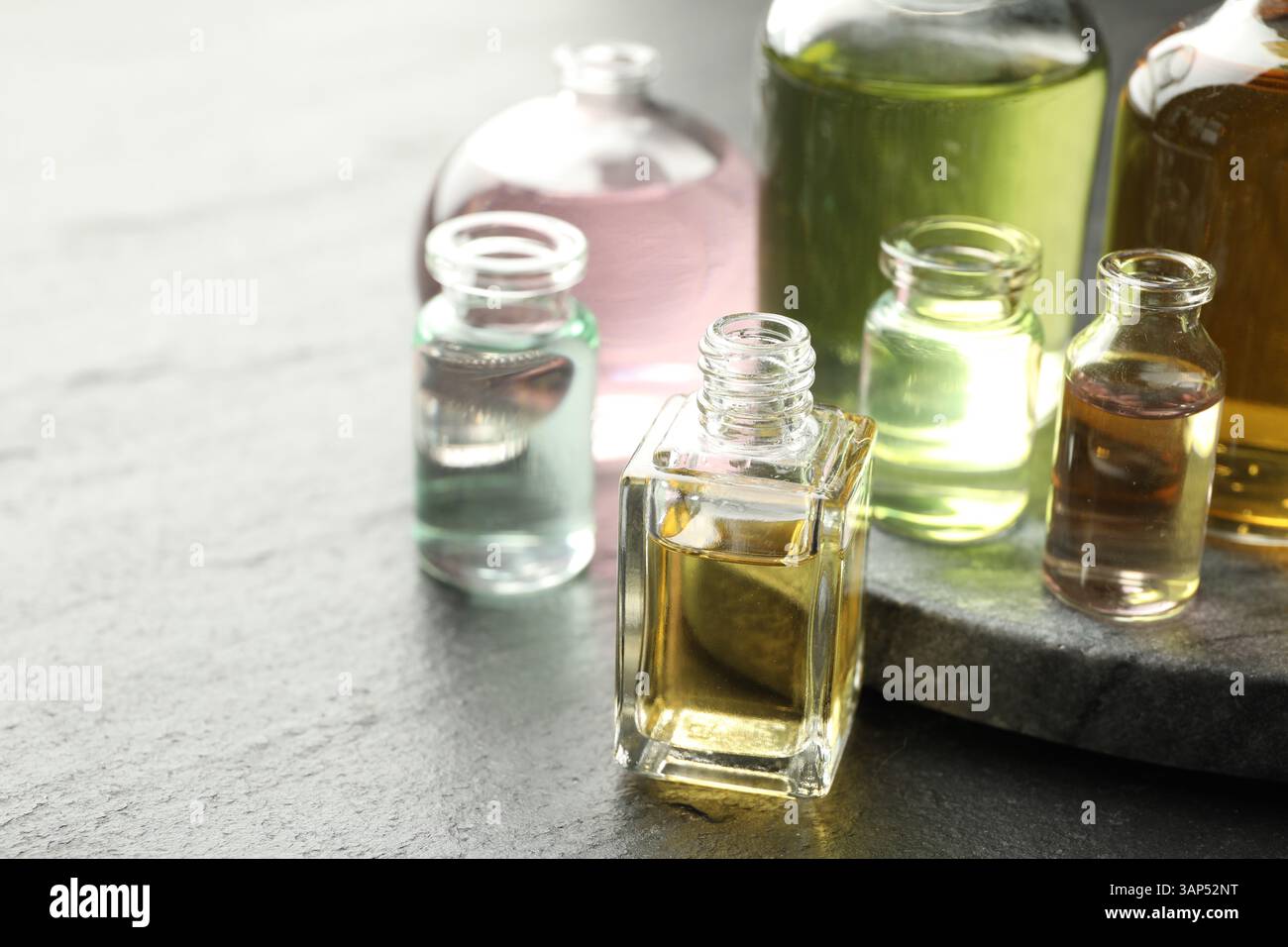 Open perfume bottles with aromatic essential oils on dark textured ...