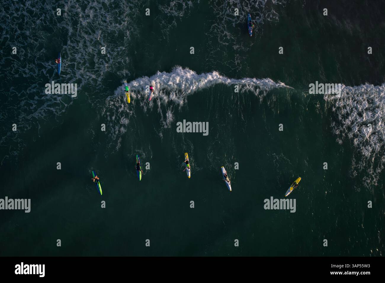 Aerial view of paddle boards on the ocean with waves and people ...