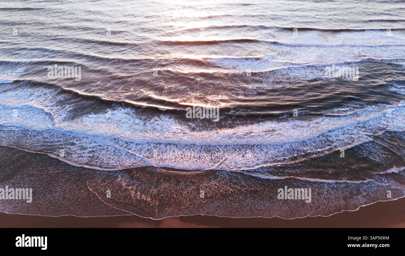 Layered Ocean Waves Rolling Onto Shore at Sunset Stock Photo - Alamy