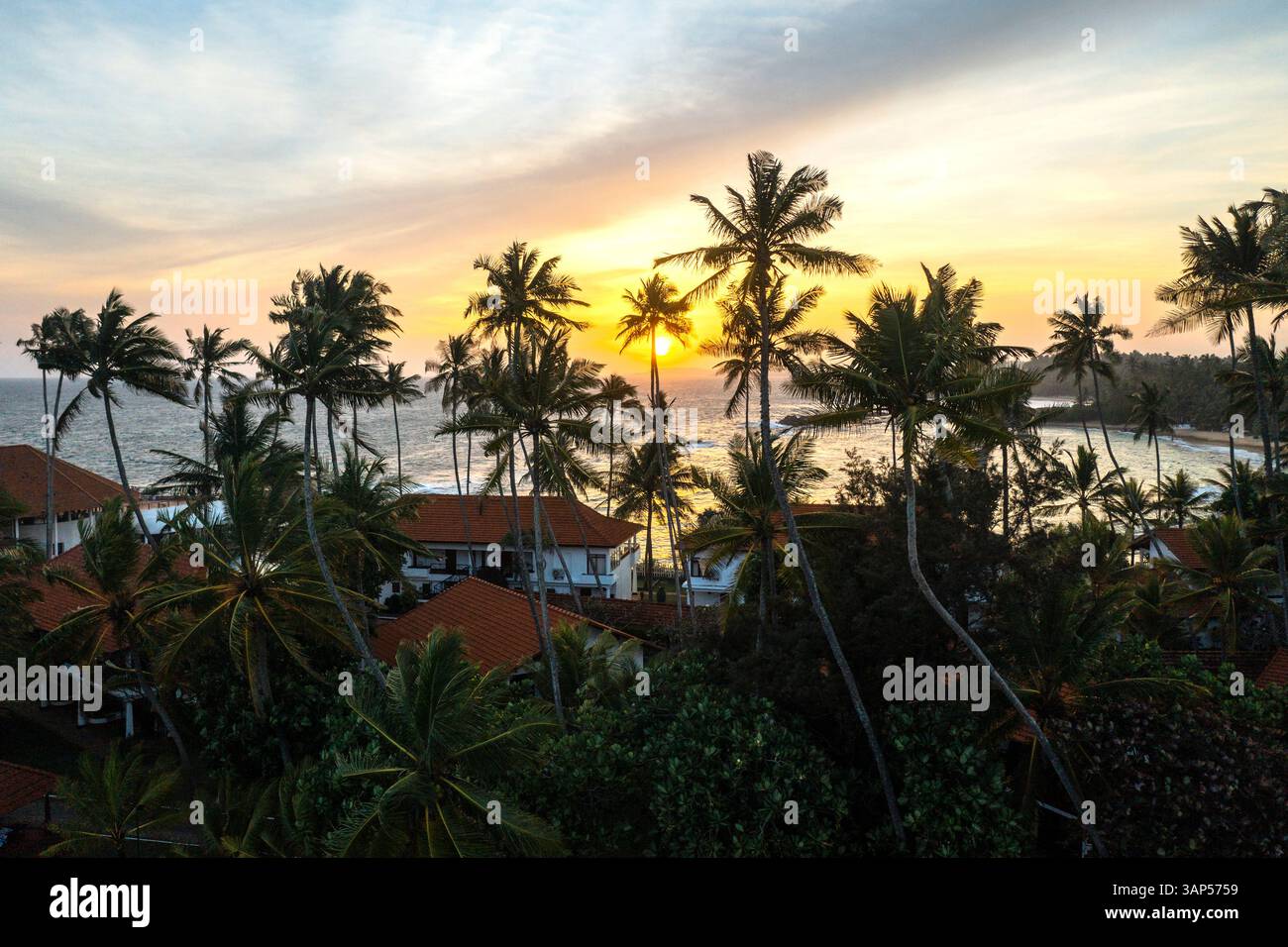 Aerial view of sunset view with palm trees and sun over Indian ocean ...