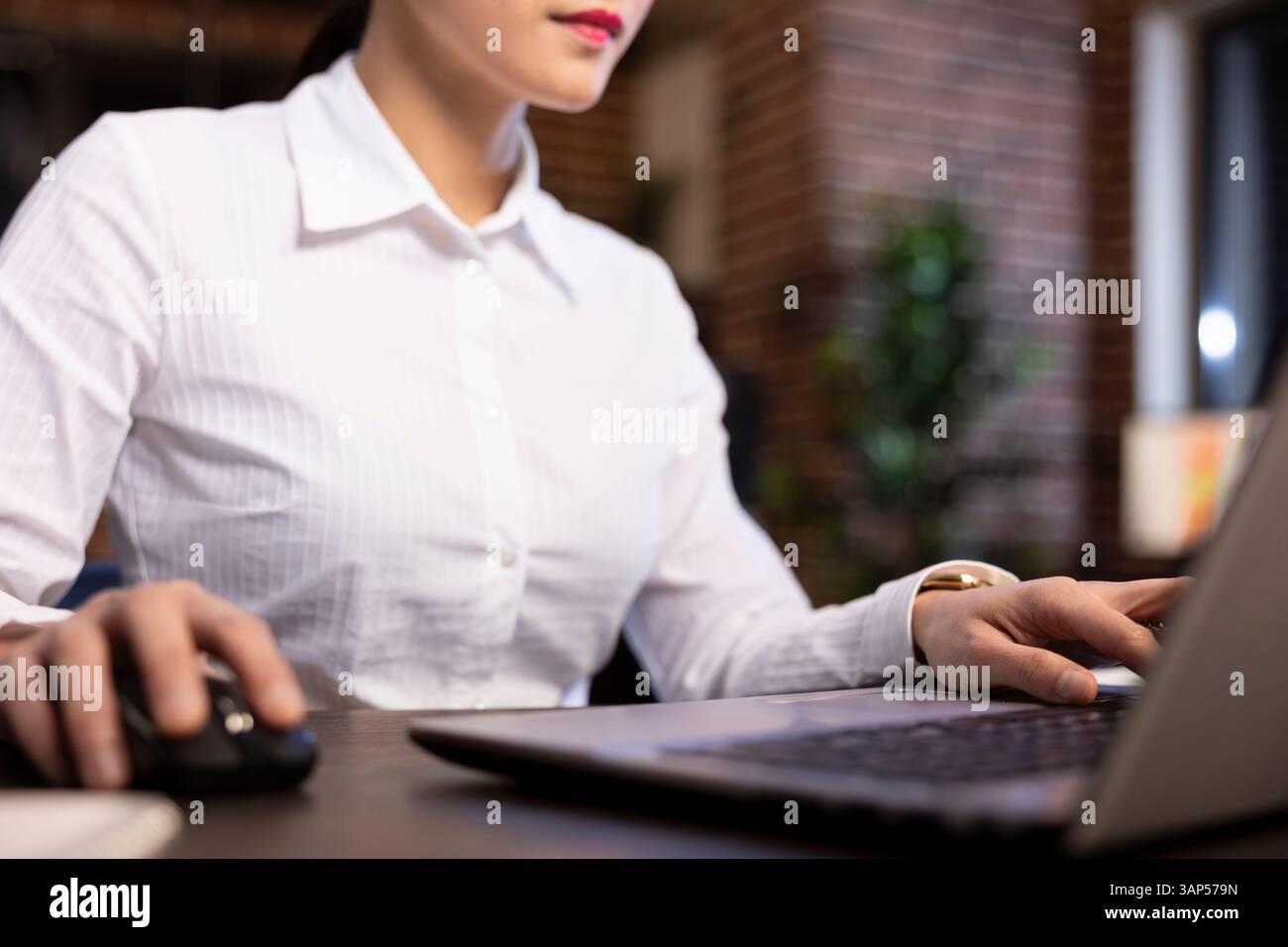 Asian female professional typing diligently on her laptop at her office ...