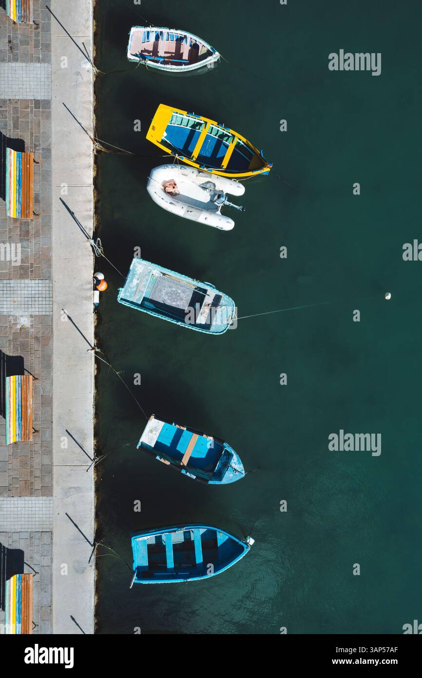 Aerial top down view of colourful tiny boats floating along pier ...