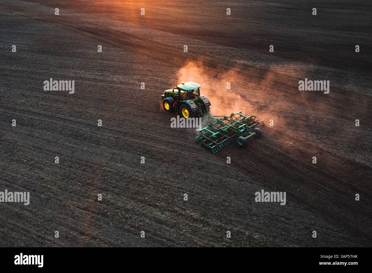 Aerial view of tractor with harrow in the agricultural farmland soil ...