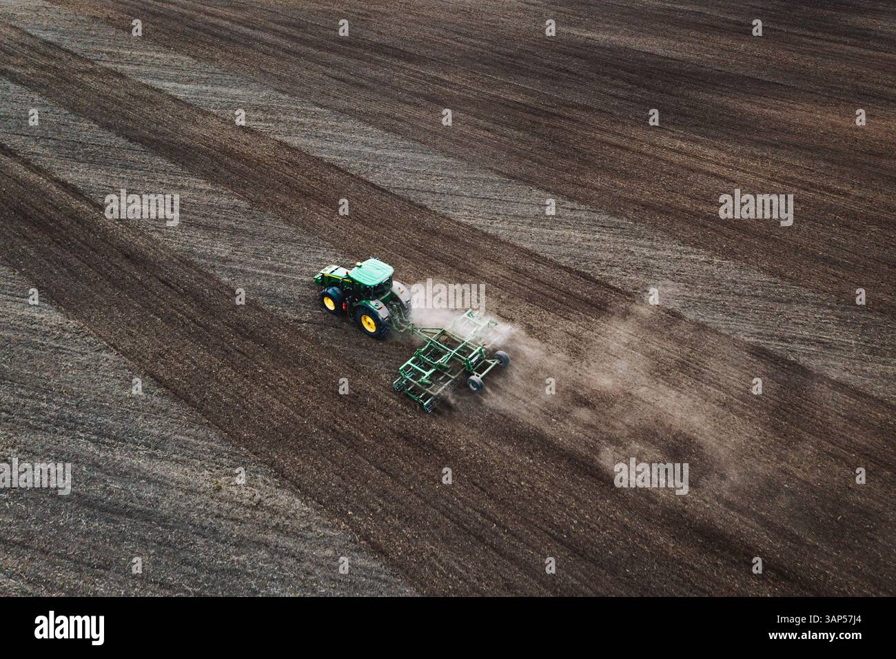 Aerial view of tractor harrowing agricultural dirt field in farming ...