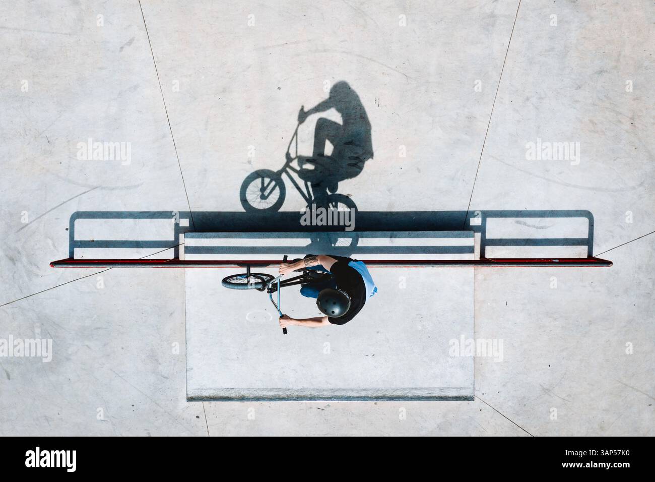 Aerial view of BMX bike rider silhouette shadow grinding rail in ...