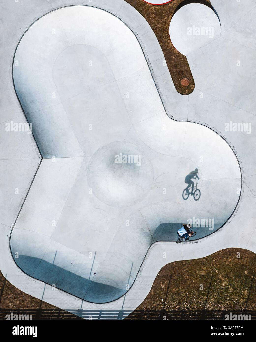 Aerial view of BMX bike rider silhouette shadow in concrete skate pool ...