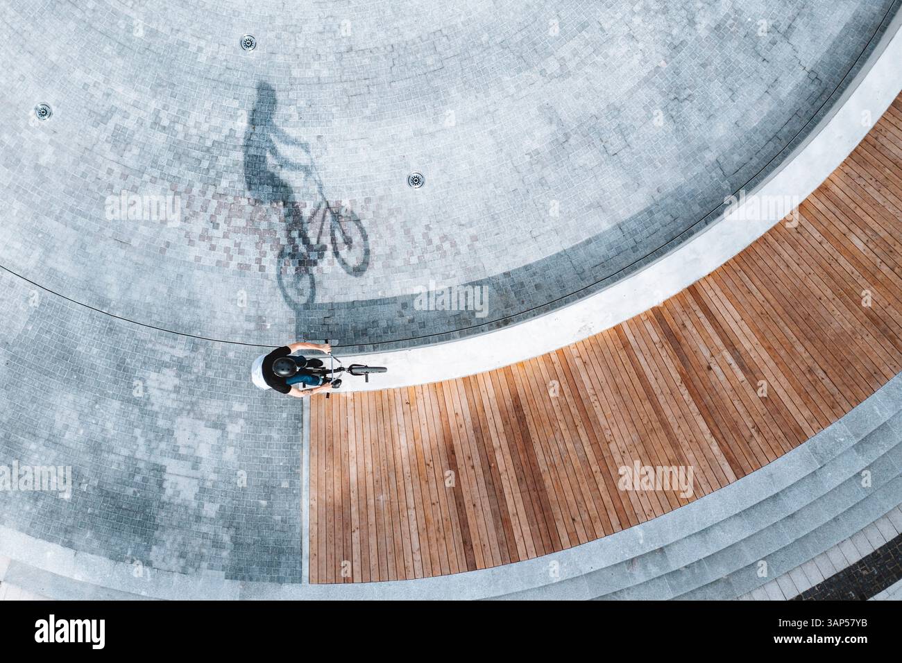 Aerial view of BMX bike rider doing wheelie in central city square in ...