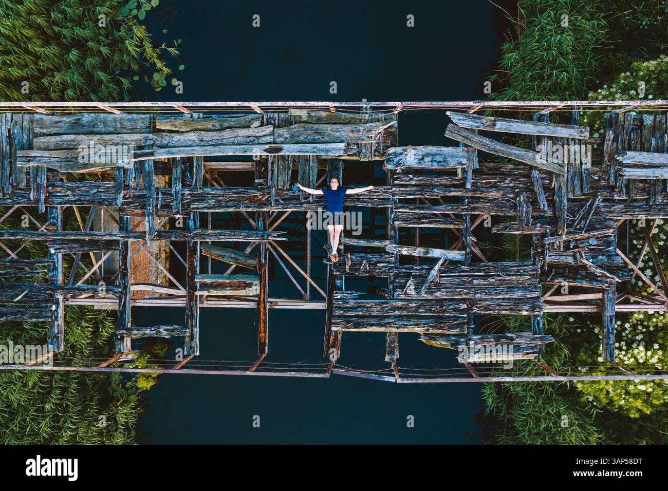 Aerial view of person lying down on old wooden collapsed bridge in ...