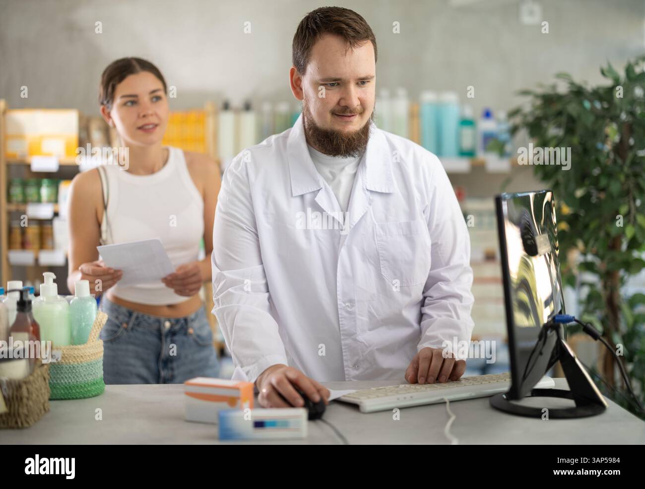 Male pharmacist helps female customer find prescription medication ...
