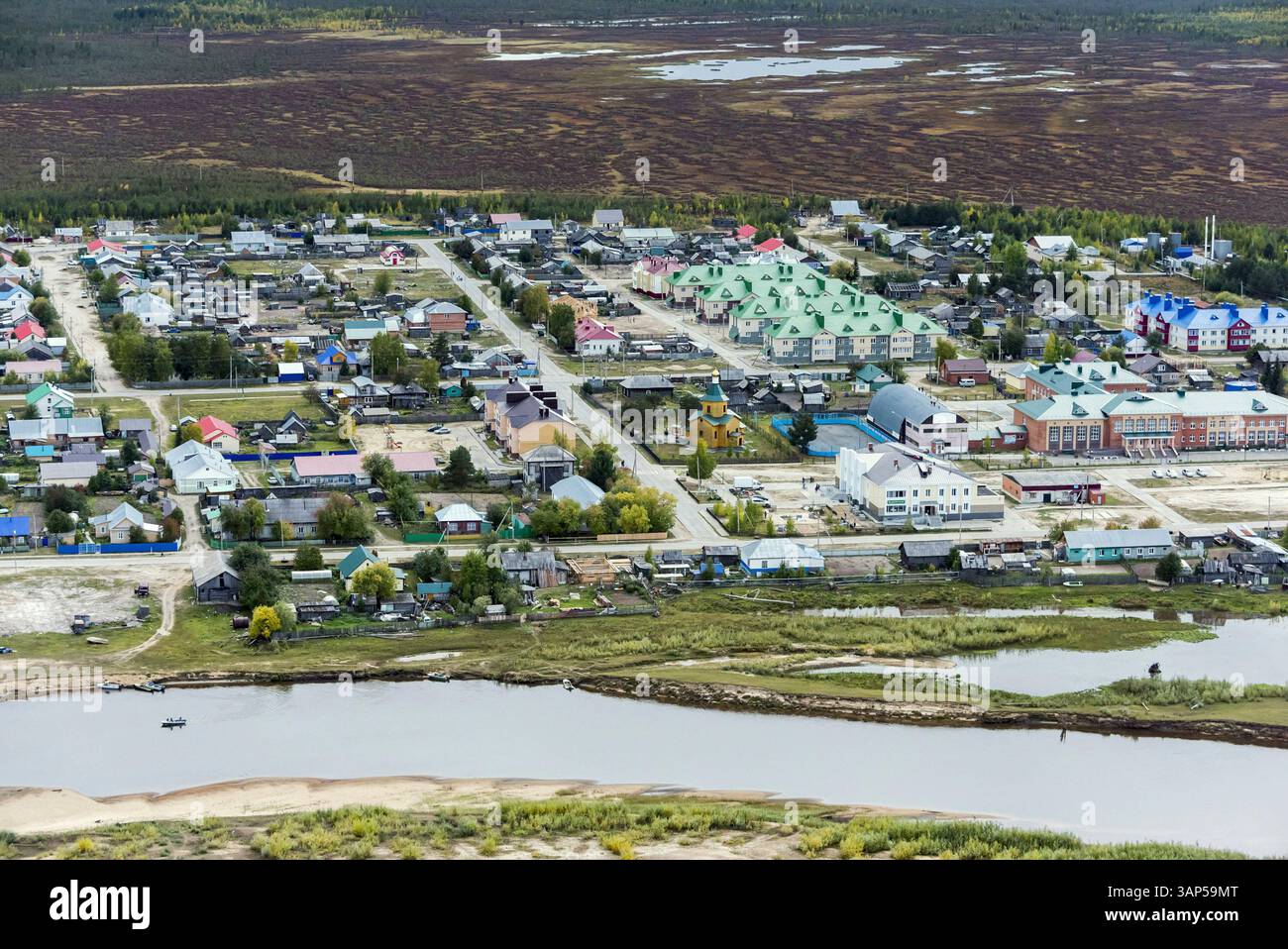 Aerial view of a tranquil suburban town with green roofs and a winding ...