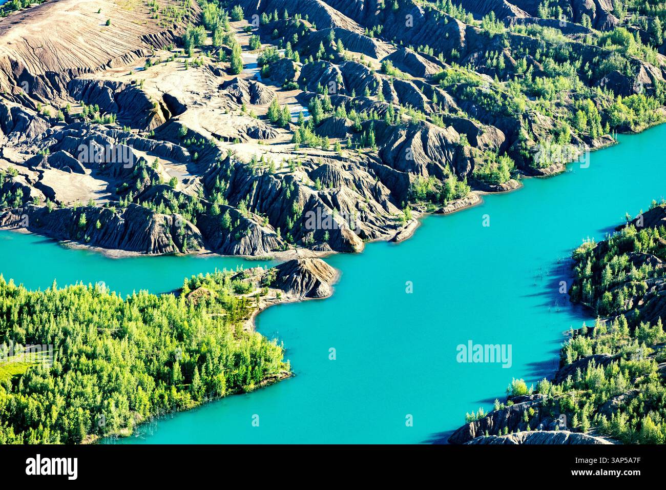 Aerial view of artificial mound of waste rock with river and forest ...
