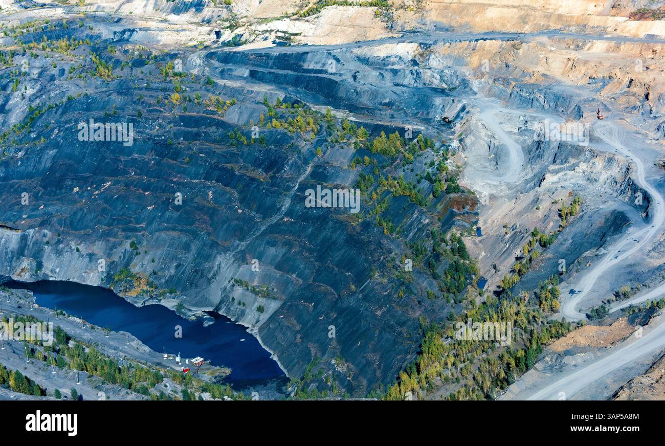 Aerial view of a beautiful pit mine surrounded by rugged terrain and ...