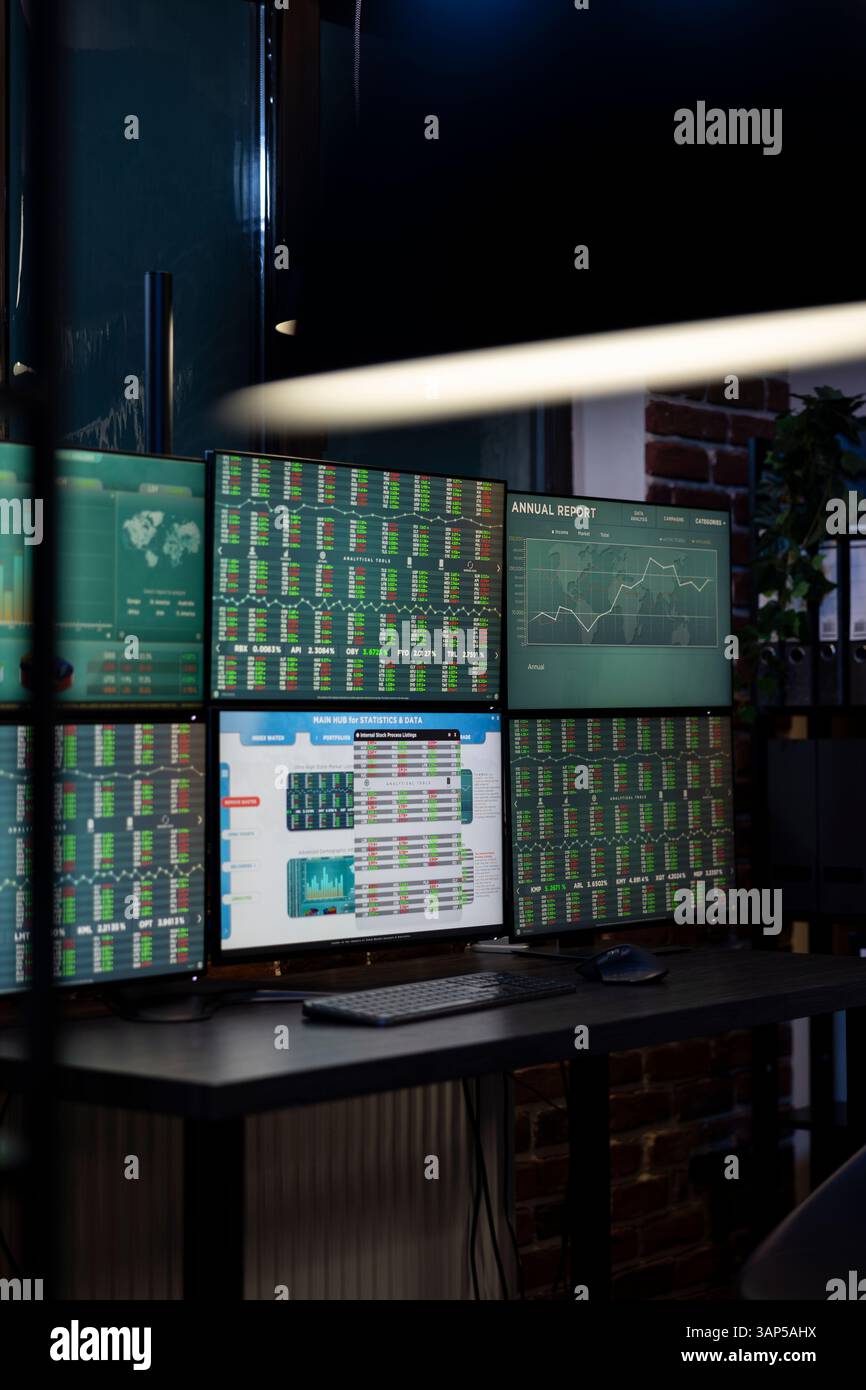 Vacant workstation with multiple monitors displaying forex charts, arranged in a modern office ...