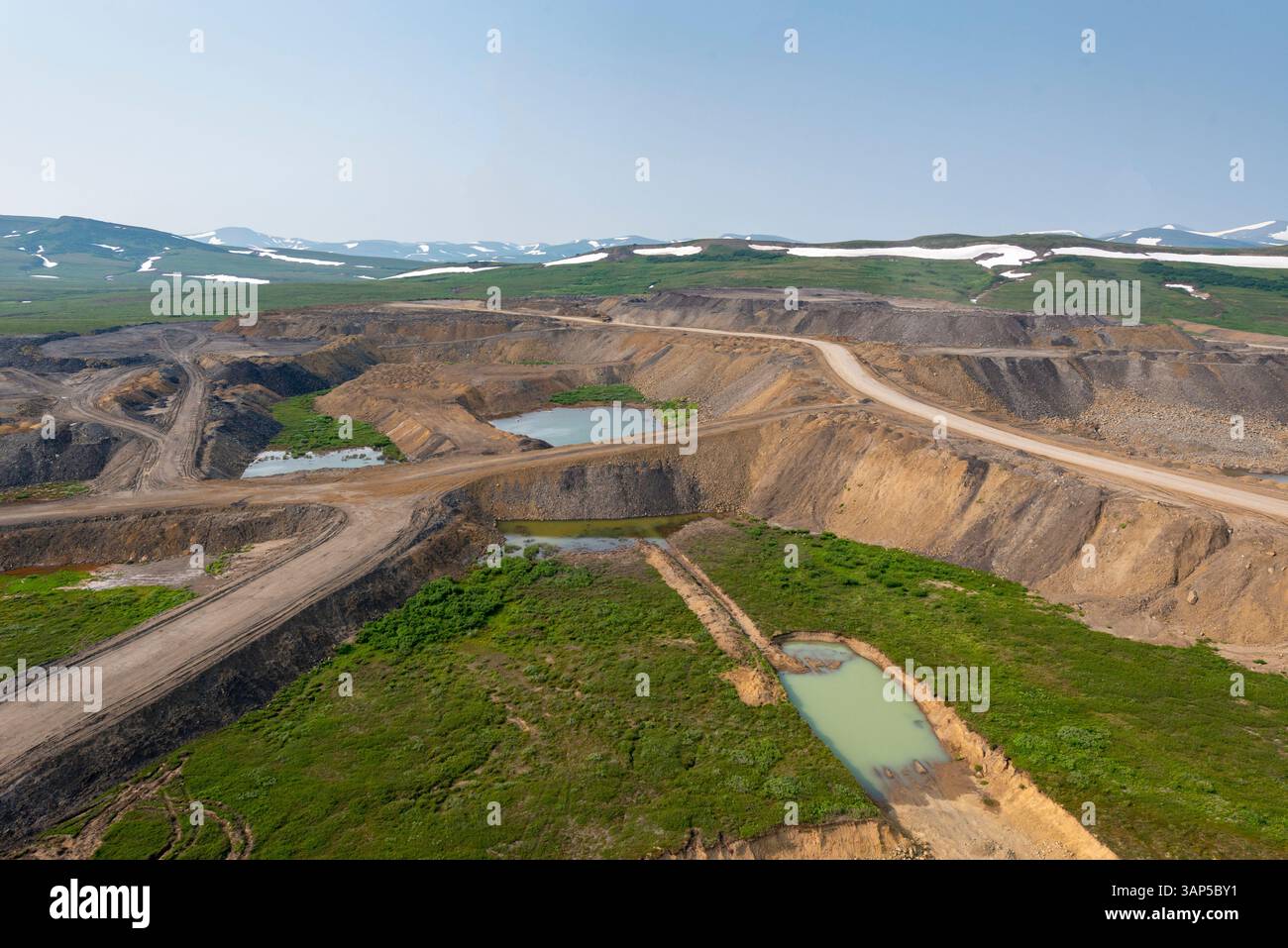 Aerial view of a rugged mining site with pits and greenery surrounded ...