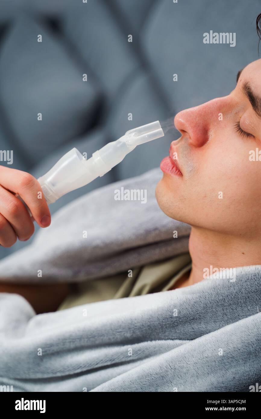 Young man with asthma attack breathing with inhaler in the bad. Doing ...