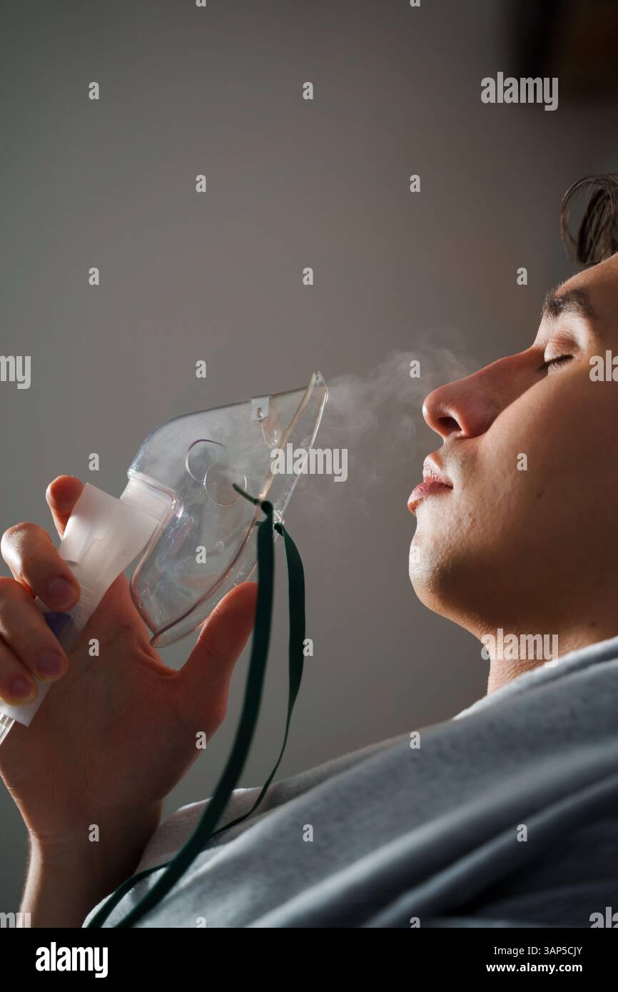 Using compressor nebulizer for disease treatment at home. Man inhaling ...
