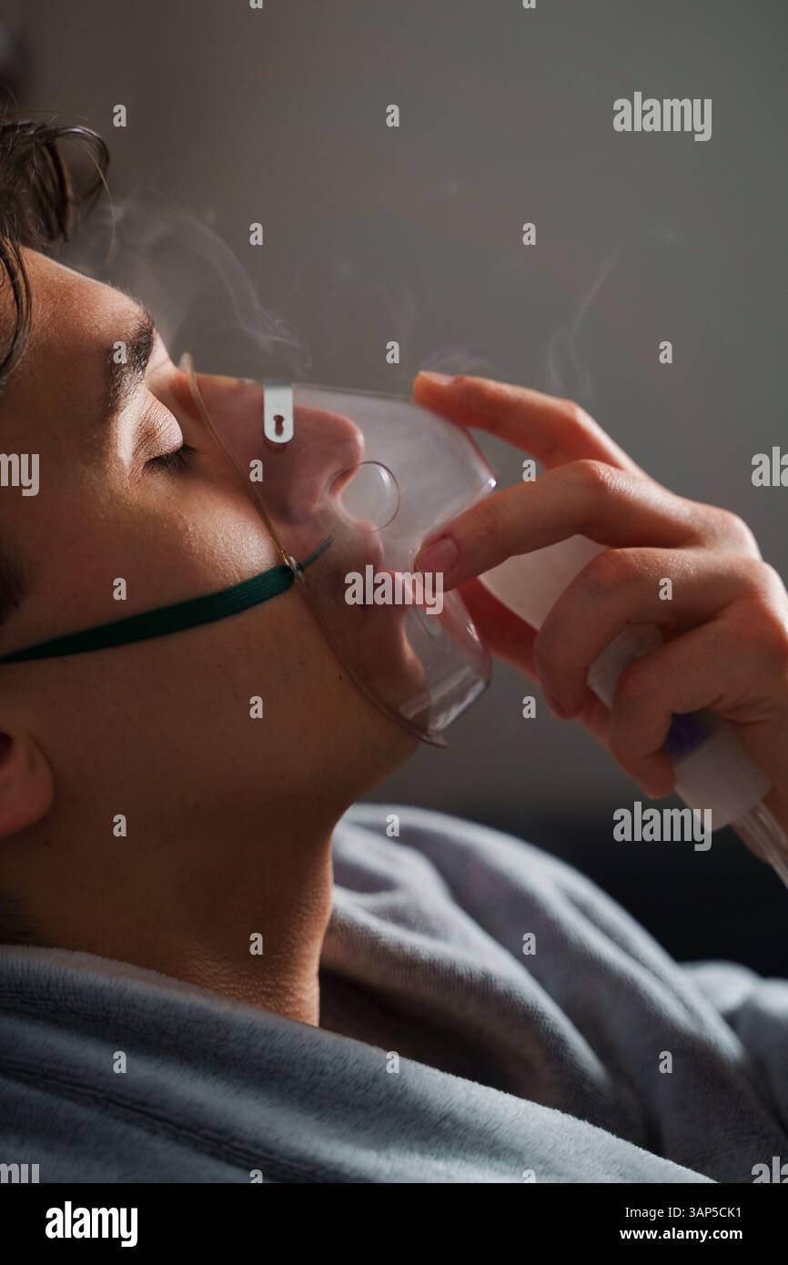 Using compressor nebulizer for disease treatment at home. Man inhaling ...