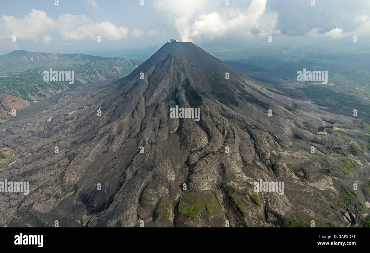 Aerial view of majestic Karymsky Volcano with smoke and clouds in a ...