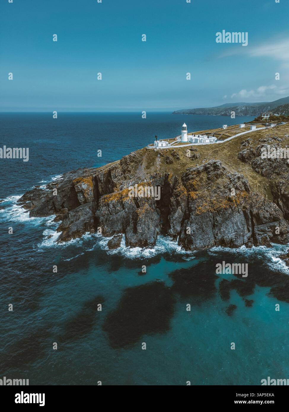Aerial view of a majestic lighthouse on a rugged cliff overlooking the ...
