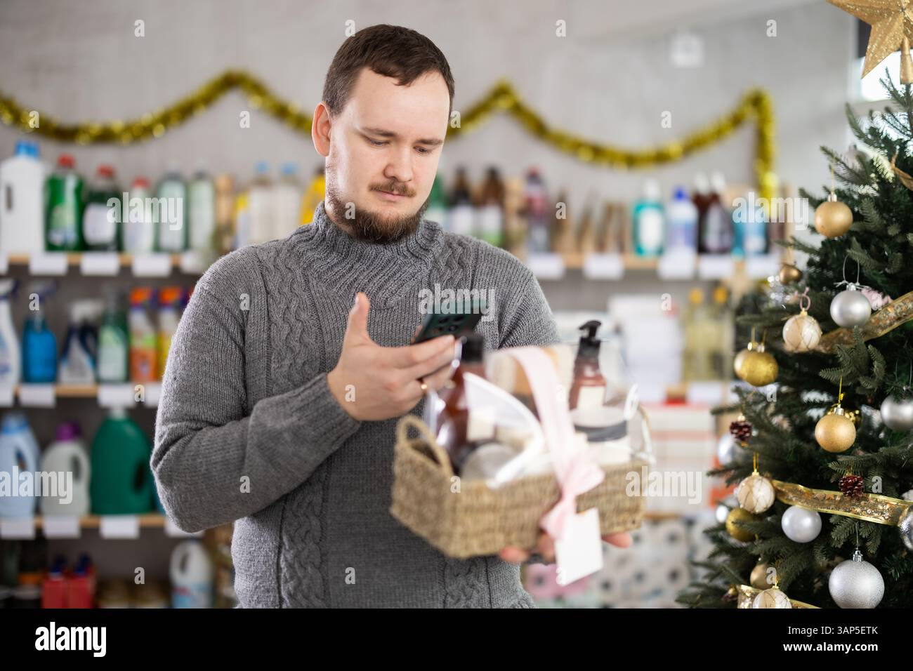 Man scanning barcode on toiletry gift set in festively decorated store ...