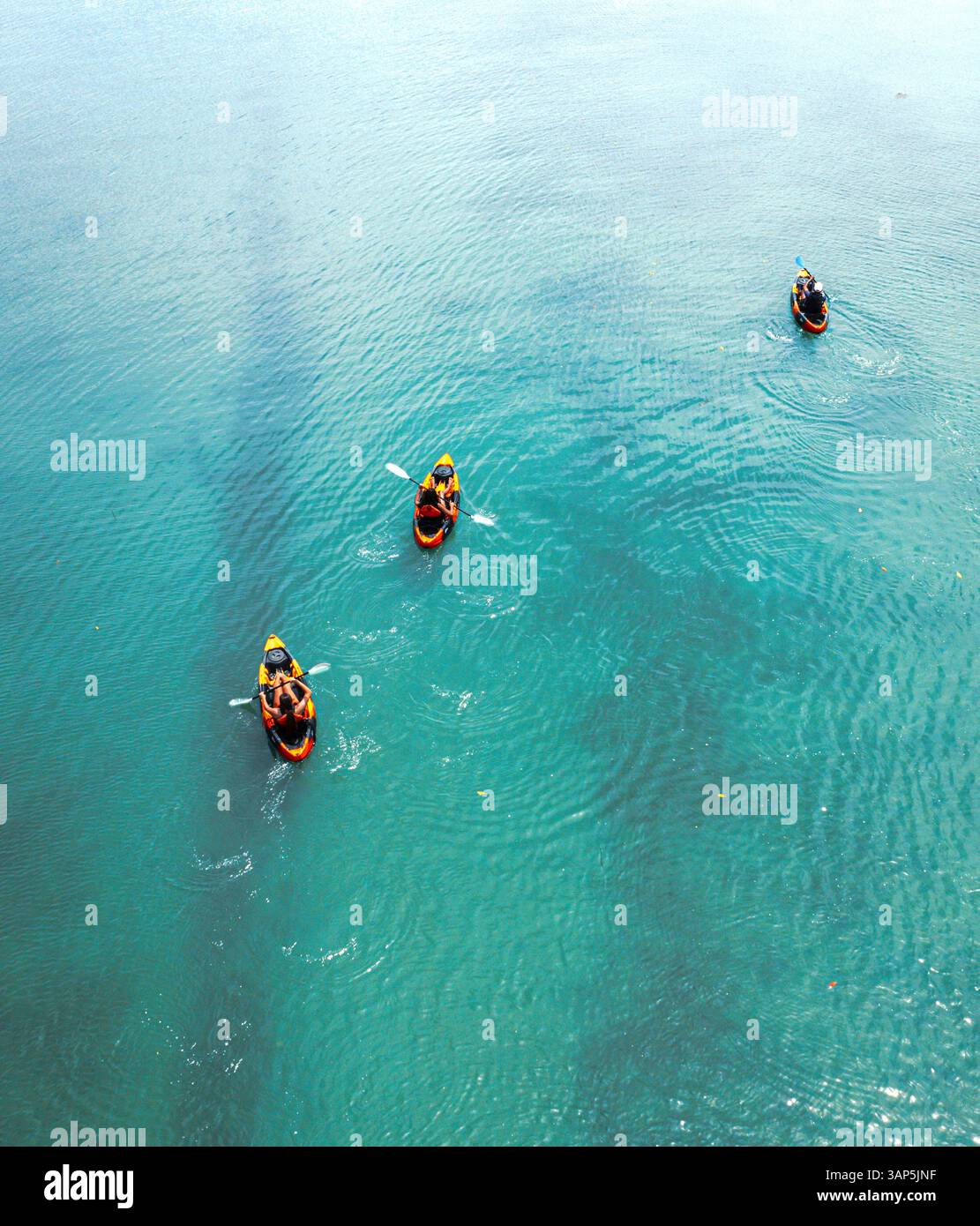 Aerial drone view of three people canoeing in orange - black canoes in ...